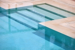 Piscina com água cristalina e padrões geométricos em azulejos.