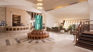 Um hall amplo com área de estar central, balcão de recepção e escadaria.