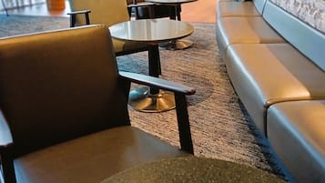 Uma área de estar moderna com um sofá, cadeiras e mesas.