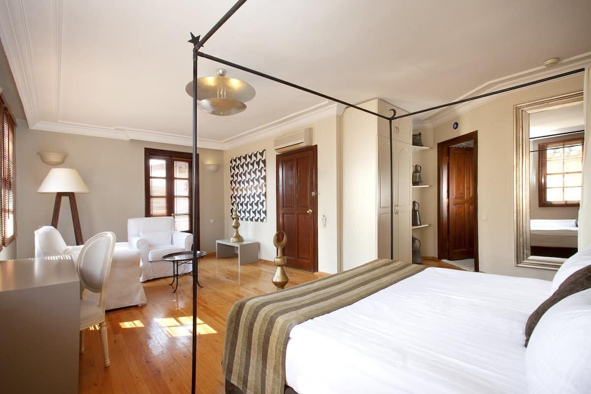 Quarto com cama, escrivaninha, cadeira, luminária e espelho.