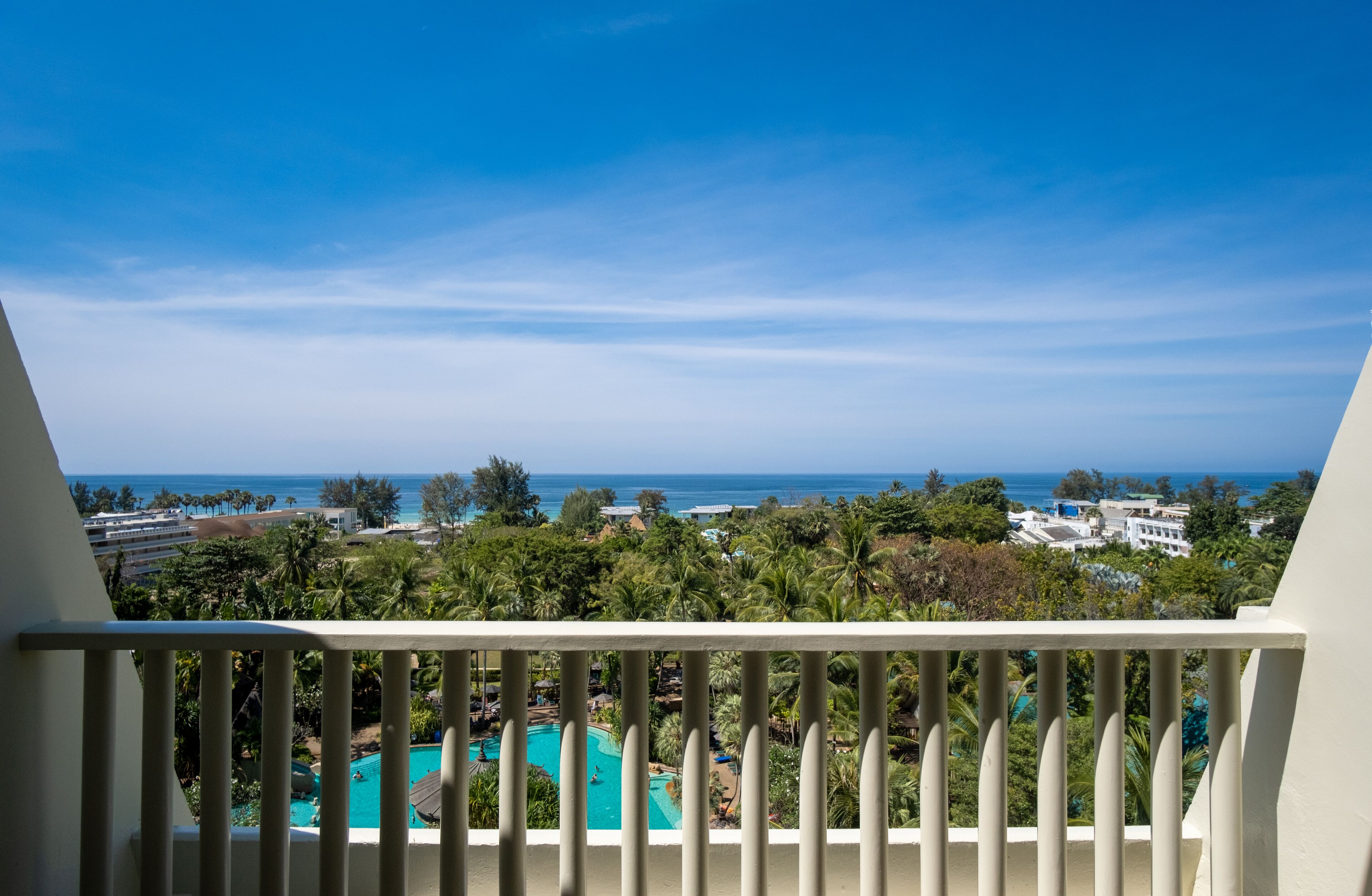 Uma varanda com vista para uma piscina e o oceano.