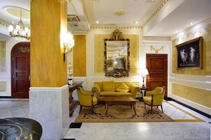 Um hall com um sofá amarelo, um espelho grande e um lustre.