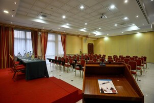 Uma sala de conferências com palco, fileiras de cadeiras e um púlpito.
