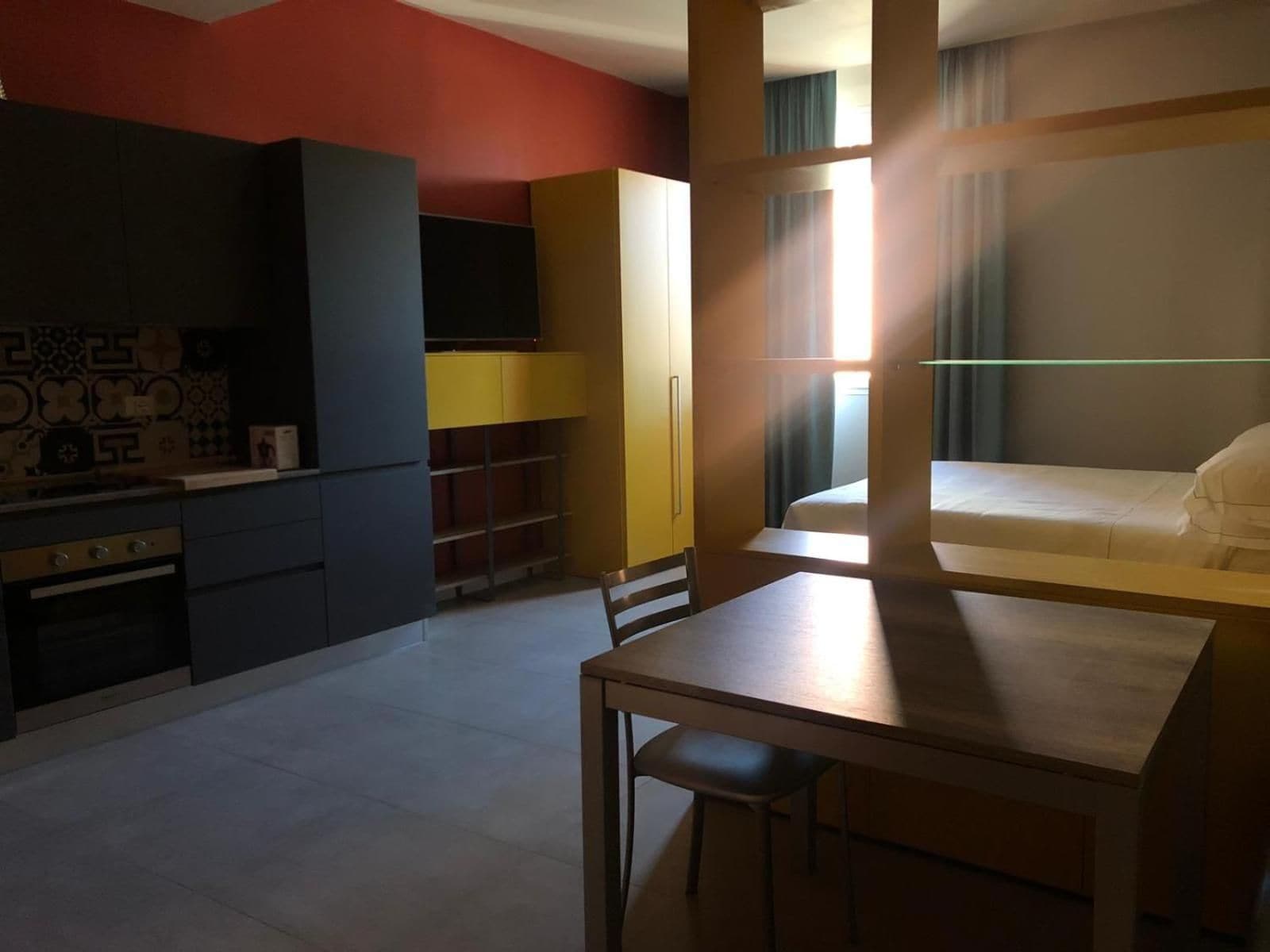 Quarto compacto com cozinha compacta, espaço de refeições e uma cama.