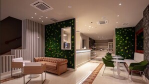Um interior moderno com sofá, cadeiras, uma sala de jantar e uma cozinha ao fundo.