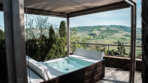 Banheira de hidromassagem com vista para colinas ondulantes e céu claro.