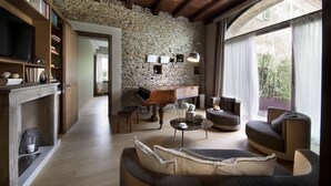 Uma sala de estar ampla com parede de pedra, um piano e uma janela grande com cortinas.