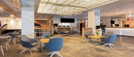 Um lobby moderno com design geométrico no teto, áreas de estar e um balcão de recepção.
