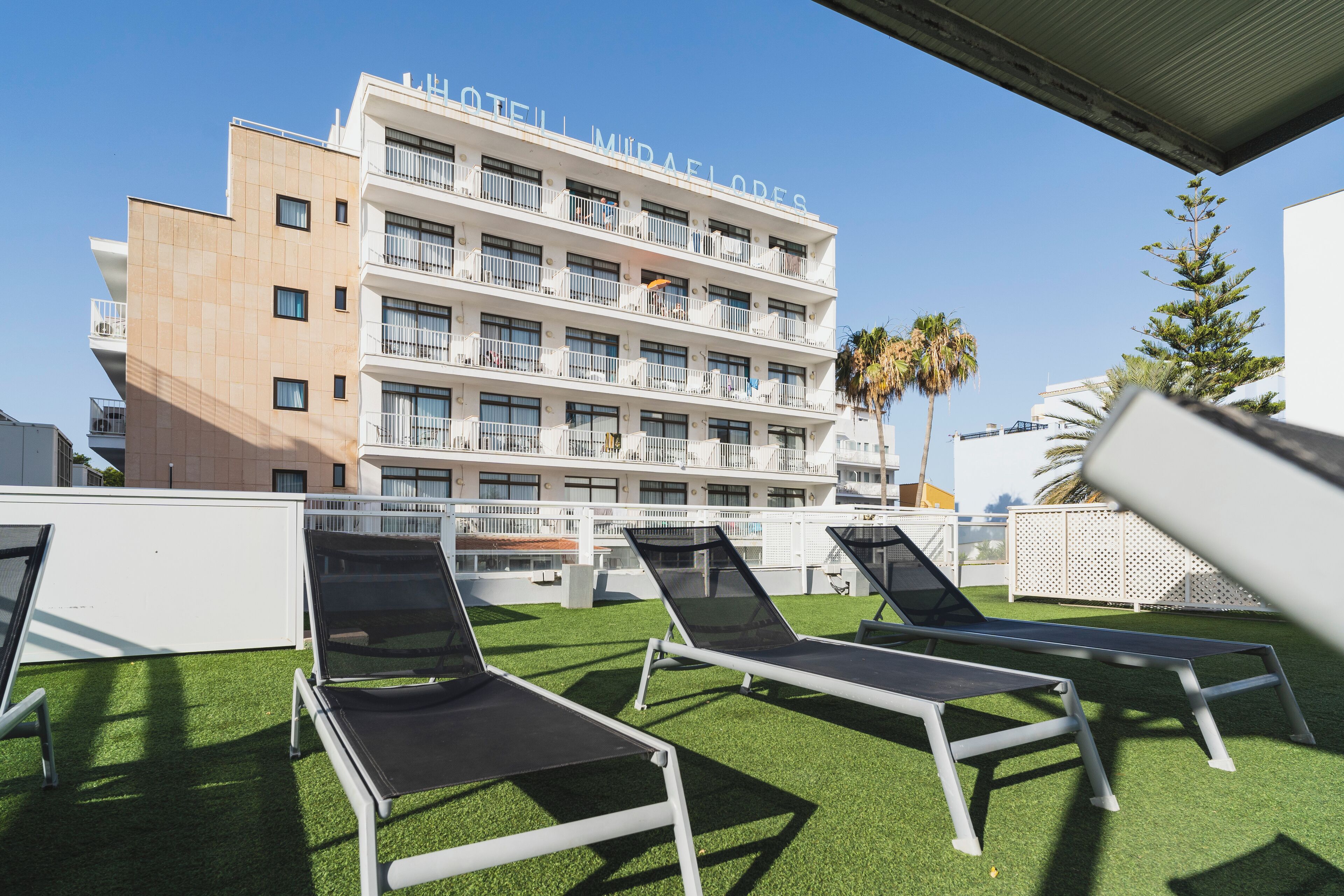 Hotel com várias varandas e área de lounge no terraço, incluindo espreguiçadeiras.