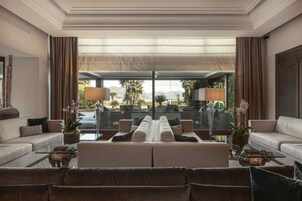 Um saguão de hotel moderno com uma ampla área de estar, uma mesa de centro de vidro e vista para o exterior.