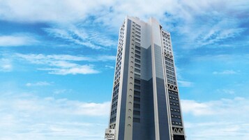 Um hotel moderno e imponente com projeto arquitetônico marcante, destacando-se por um elemento vertical central e diversas varandas.