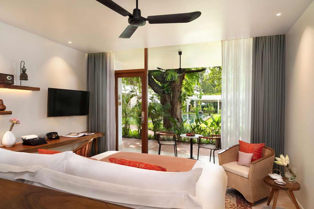 Quarto de hotel moderno com cama, escrivaninha, televisão e vista para o exterior.