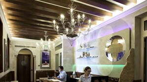 Uma área de recepção com lustre, balcão e parede decorada com vasos.