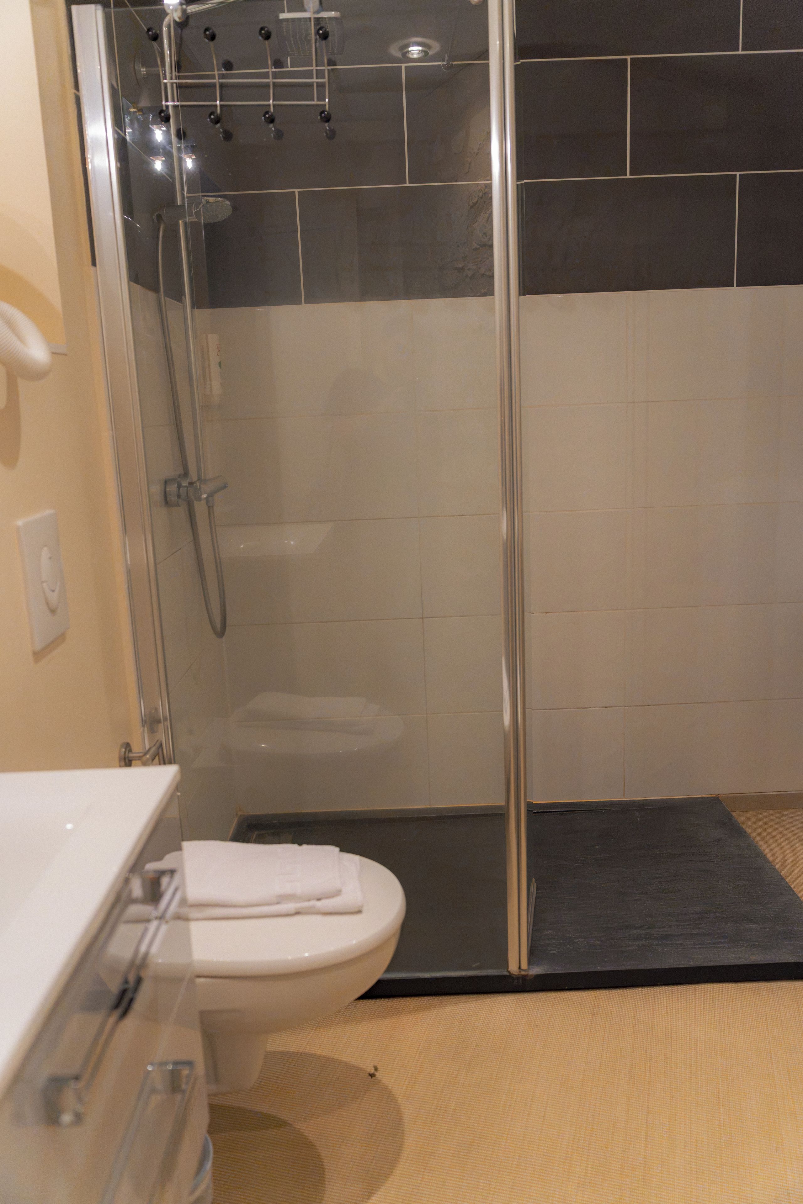 Uma casa de banho com cabine de duche em vidro, sanita e lavatório.
