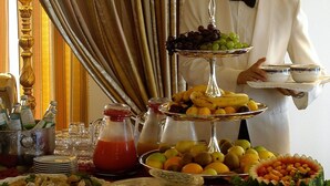 Mesa de buffet com diversos pratos e um garçom servindo.