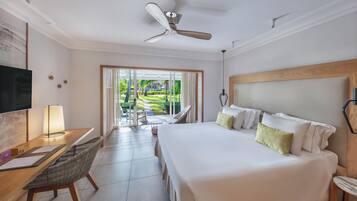 Quarto de hotel com uma cama grande, uma escrivaninha com cadeira, televisão e vista para um jardim pela janela.
