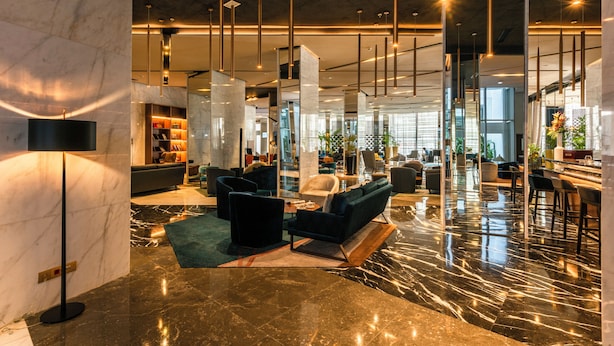 Um hall moderno com piso de mármore, um sofá, cadeiras e um espaço de bar.