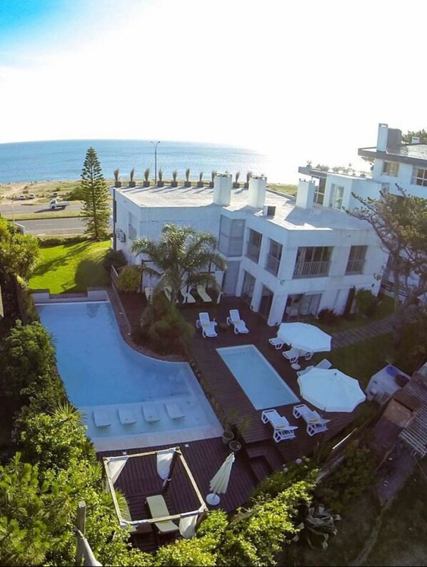 Um hotel moderno com piscina, espreguiçadeiras e vista para o oceano.