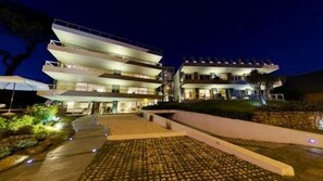 Um hotel moderno de vários andares, com um pátio central e fachada bem iluminada.