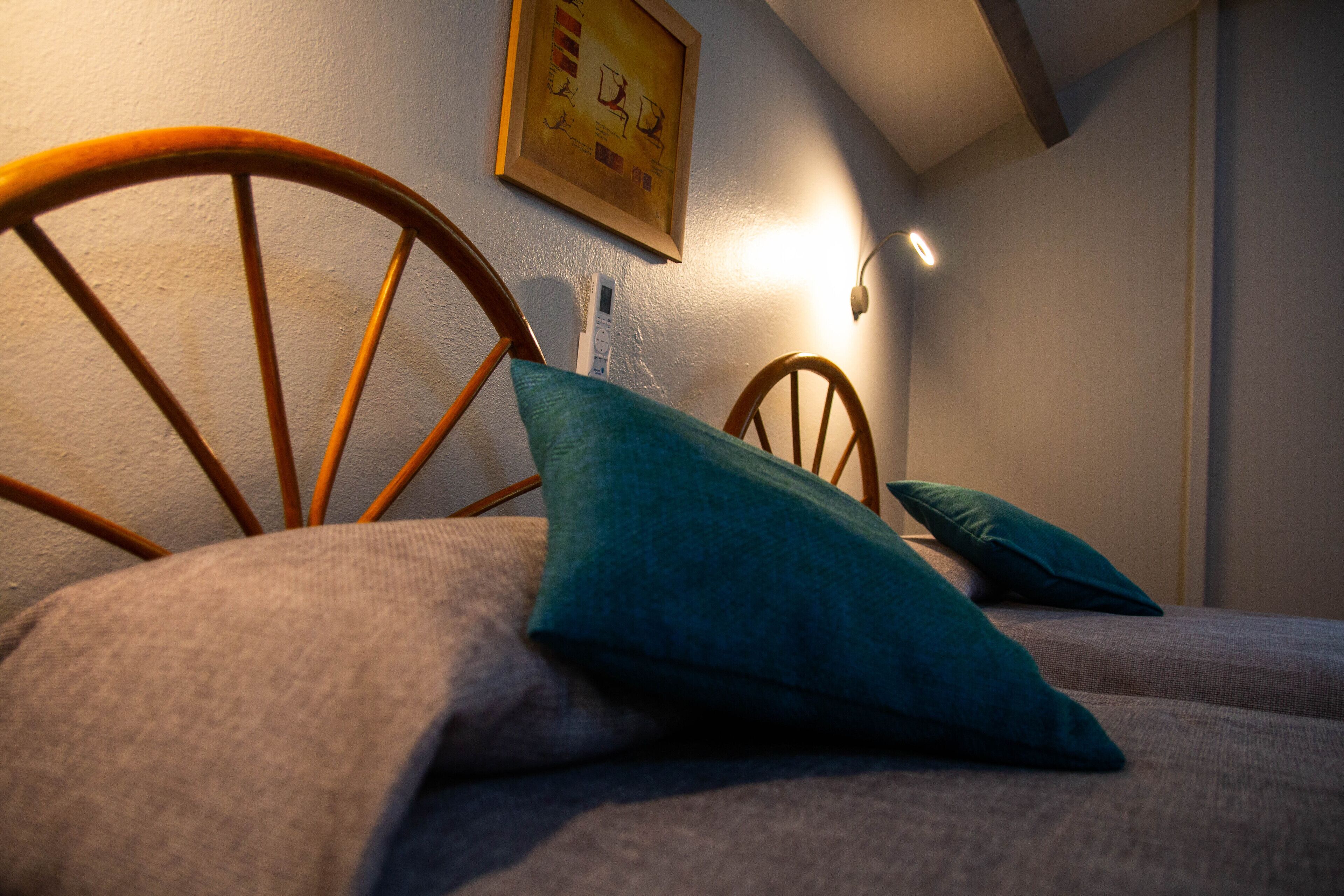 Quarto com cabeceira de madeira, um quadro na parede e uma luminária de cabeceira.