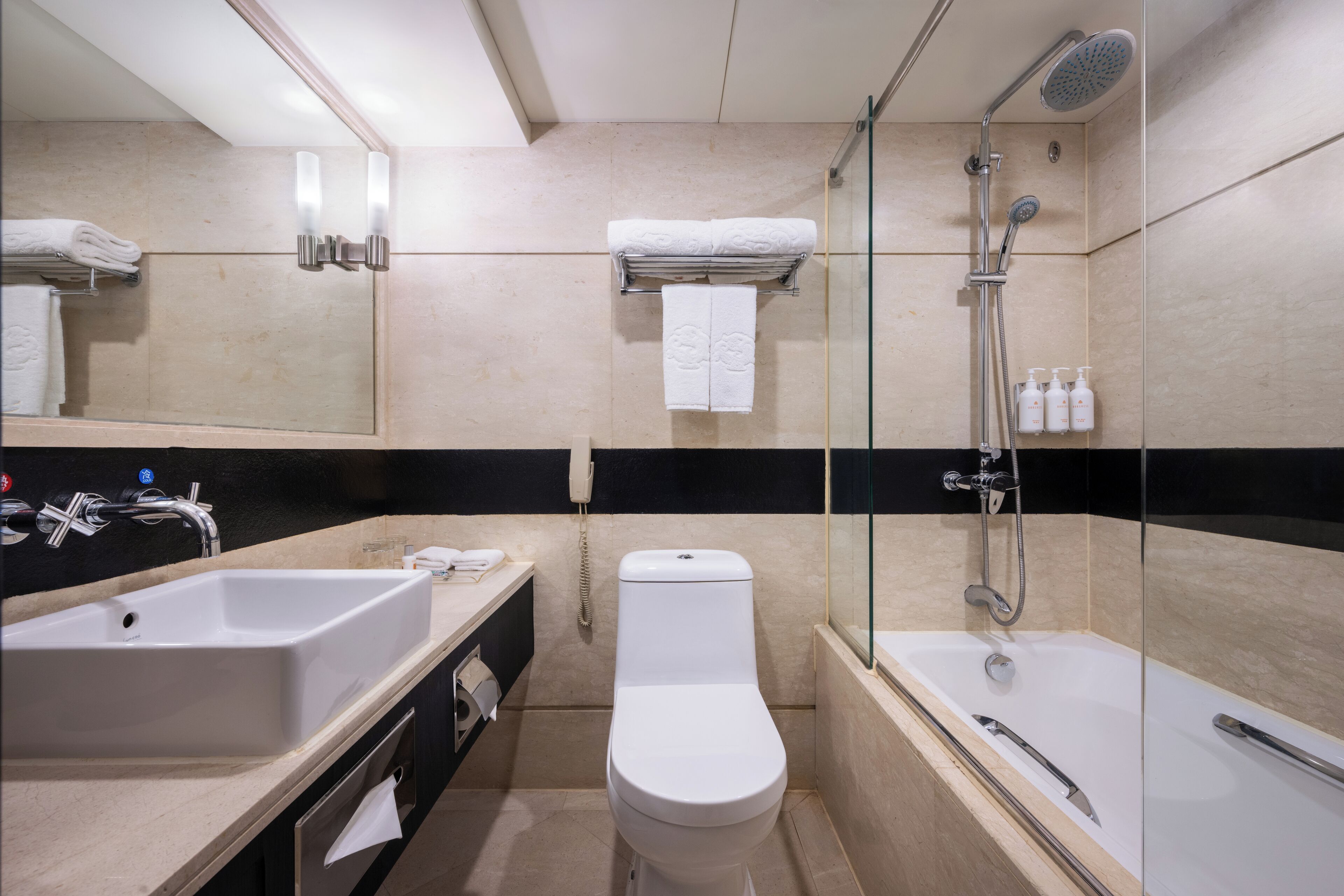 Um banheiro moderno com uma pia grande, vaso sanitário e banheira. Há toalhas e produtos de higiene no balcão.