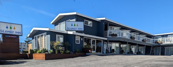 Edifício do Seaway Inn com design moderno, janelas grandes e área de estar coberta ao ar livre.