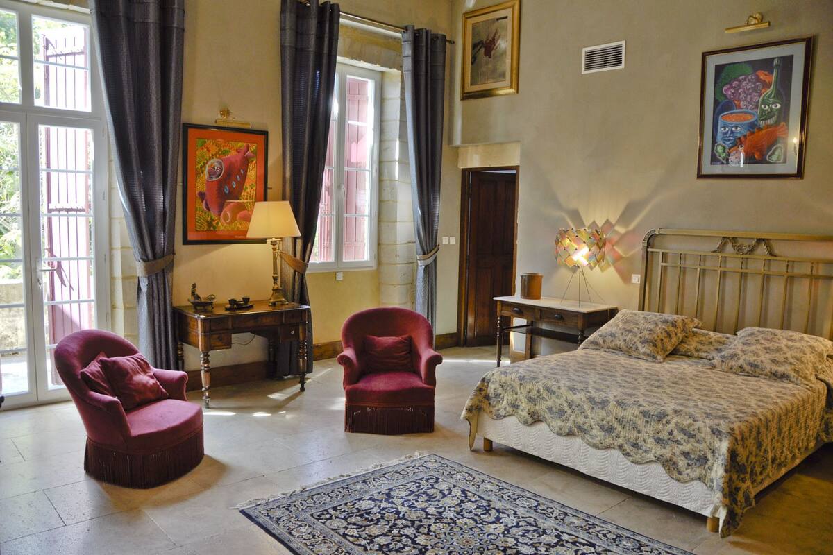 Quarto com cama, duas cadeiras, escrivaninha e abajur.