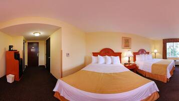 Quarto de hotel com duas camas, uma escrivaninha com cadeira, um cesto de lixo e uma porta que dá para outro cômodo.