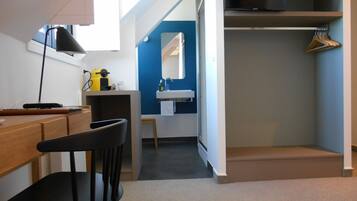 Quarto compacto com escrivaninha, cadeira e televisão em uma prateleira.