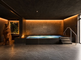 Uma área de spa com hidromassagem, piso em azulejo e uma parede com jardim vertical.
