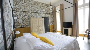 Quarto de hotel com uma cama grande, um guarda-roupa, uma televisão e uma janela com cortinas.