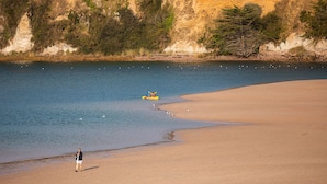 Uma praia de areia com vista clara para o mar e uma pessoa parada na orla.