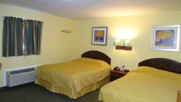 Quarto de hotel com duas camas, aquecedor, luminária e obras de arte nas paredes.