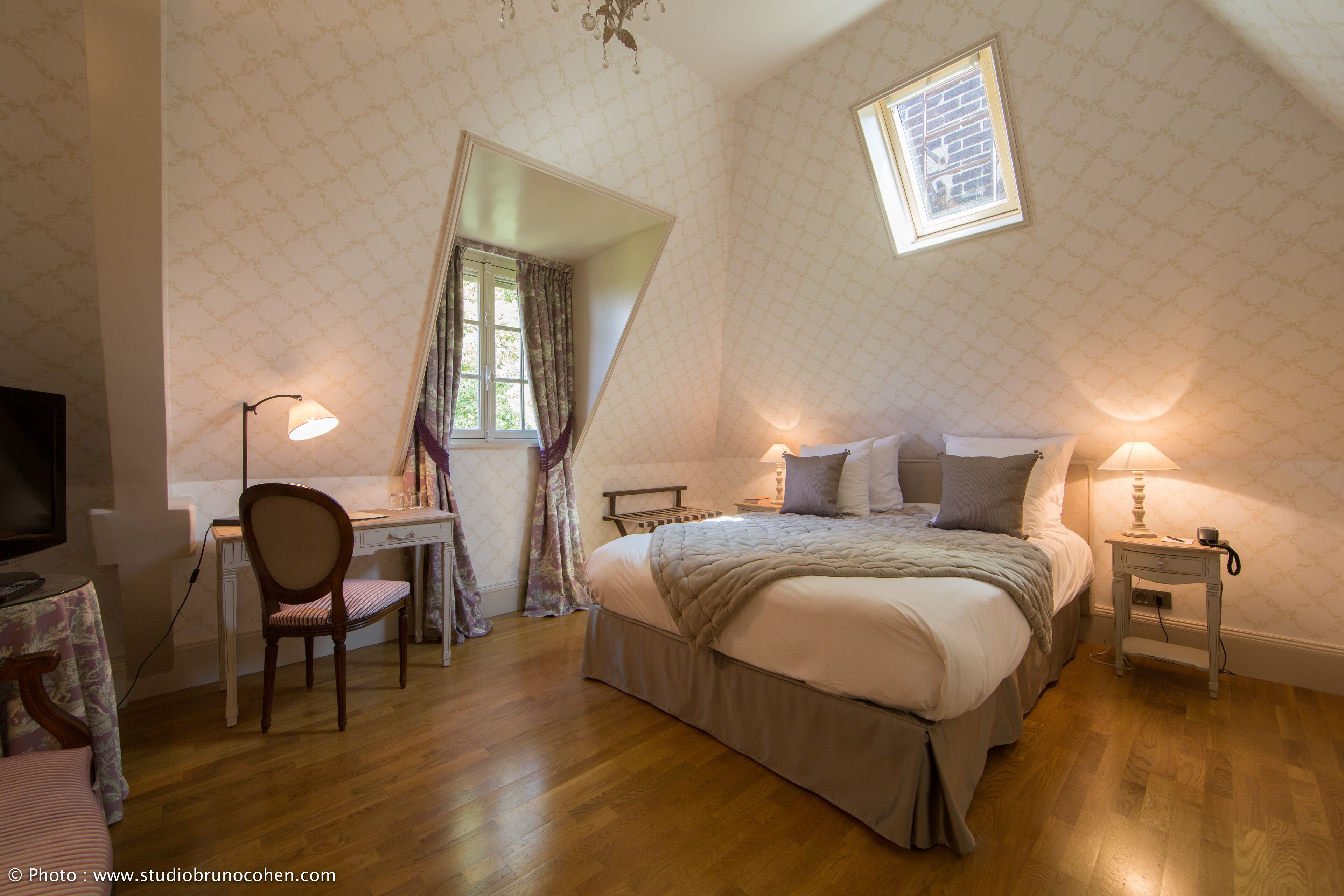 Quarto com cama, escrivaninha, cadeira e uma mesinha.