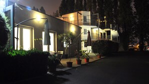 Um edifício moderno com entrada bem iluminada, plantas em vasos e área de estar ao ar livre.