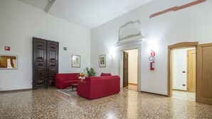 Um hall amplo com um sofá vermelho, portas de madeira e chão polido.