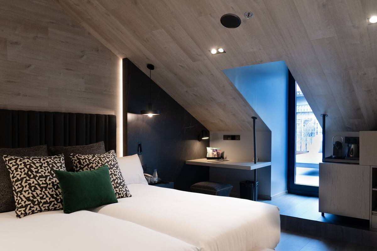 Quarto moderno com uma cama grande, uma escrivaninha e vista para o exterior.