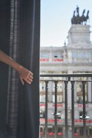 Uma varanda com grade de metal e vista para um edifício com uma estátua.