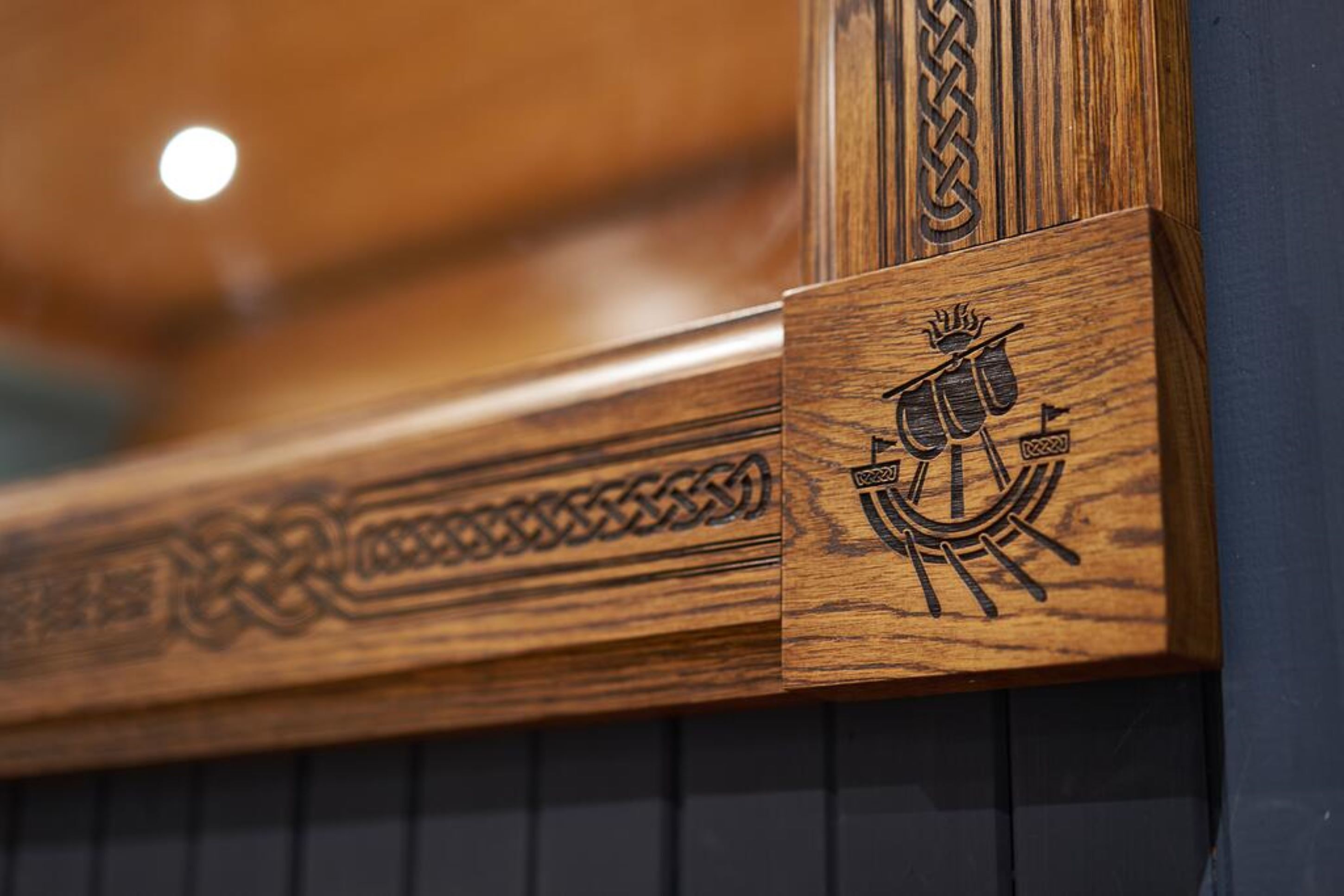 Painel de madeira com emblema entalhado e moldura decorativa.
