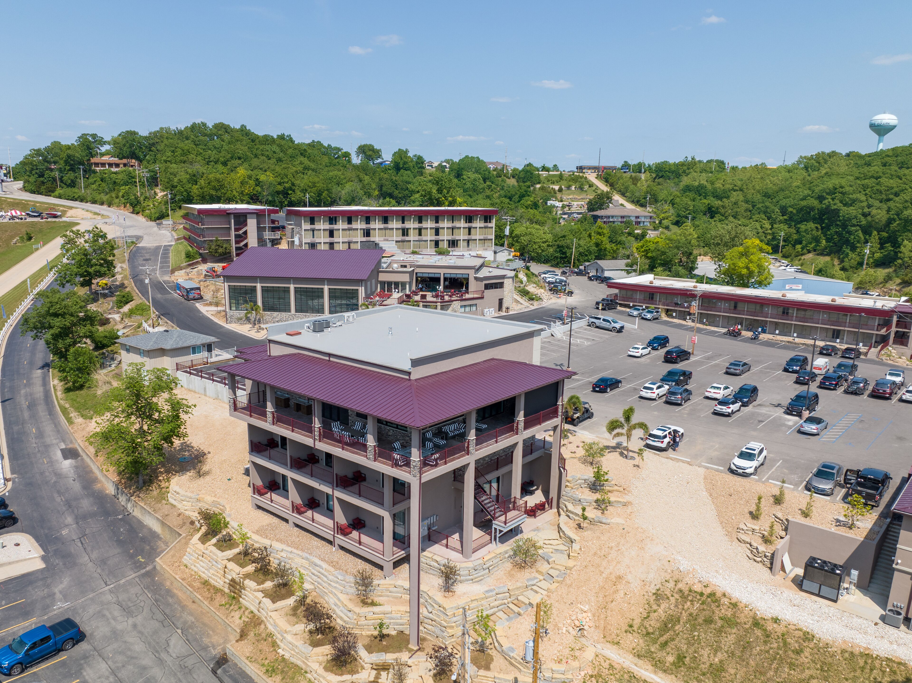 Hotel com vários andares, estacionamento, rodeado por vegetação e uma paisagem montanhosa.