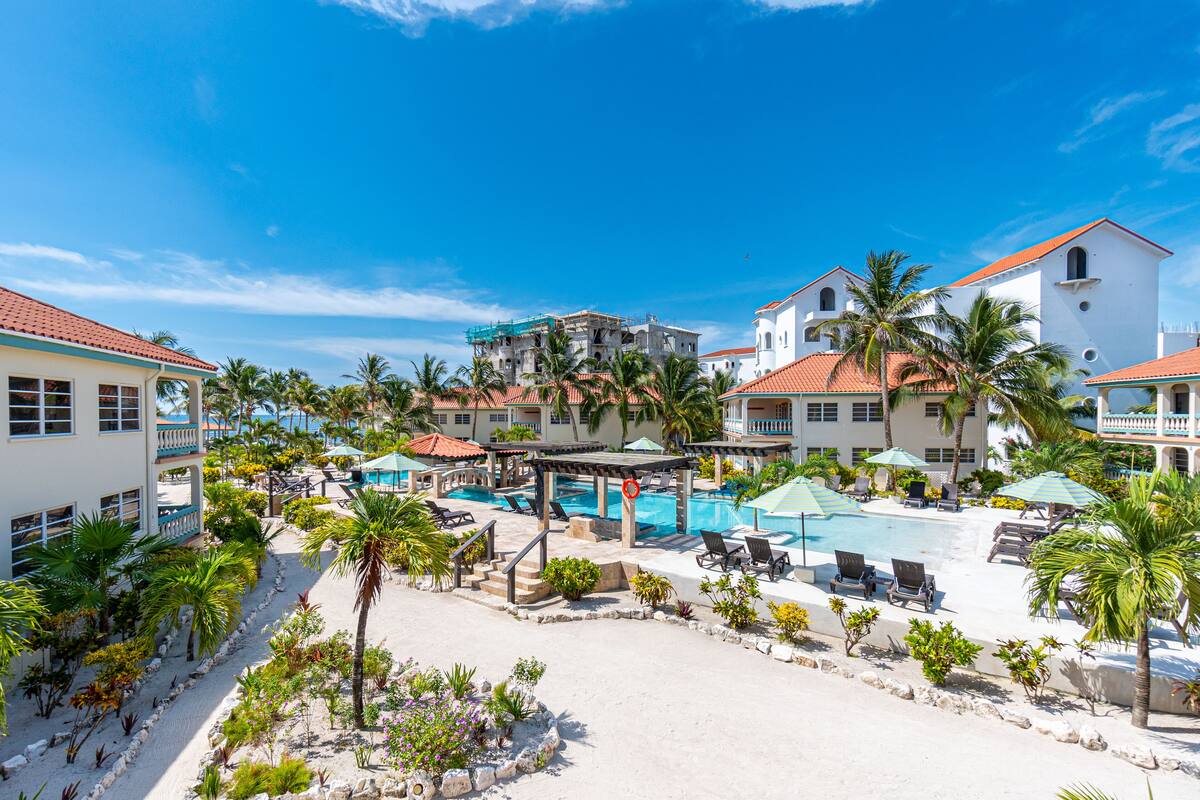 Um resort com piscina, palmeiras e área de praia.