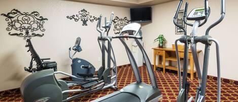 Sala de ginástica com esteiras, elíptica e bicicleta ergométrica.