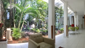 Uma área externa coberta com uma mesa e cadeiras de jantar, cercada por vegetação exuberante e diversas plantas.