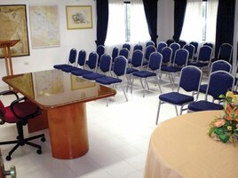 Uma sala de conferências com mesa de vidro, cadeiras azuis e uma cadeira de escritório vermelha.