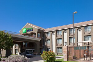 Um hotel Holiday Inn Express com entrada coberta, várias varandas e área de estar ao ar livre.