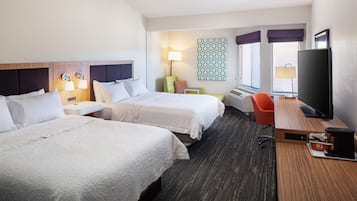 Quarto de hotel com duas camas, uma escrivaninha, televisão e uma obra de arte na parede.