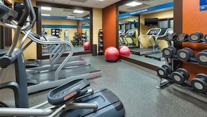 Uma academia com esteiras, halteres e bolas de ginástica.