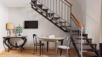 Um interior moderno com escada, mesa de jantar com cadeiras, pequena mesa lateral com luminária e um objeto decorativo na parede.