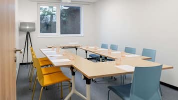 Uma sala de conferências com uma mesa comprida, cadeiras e um projetor.