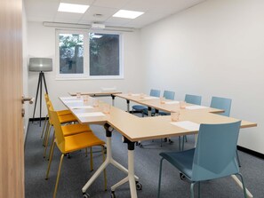 Uma sala de conferências com uma mesa comprida, cadeiras e um projetor.